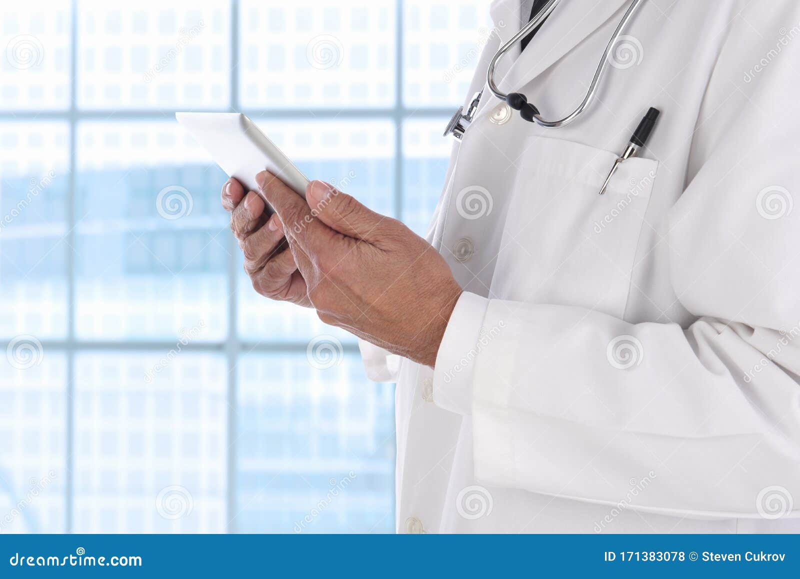 Closeup of a Doctor with a Table Computer in Front of a Large Window in ...