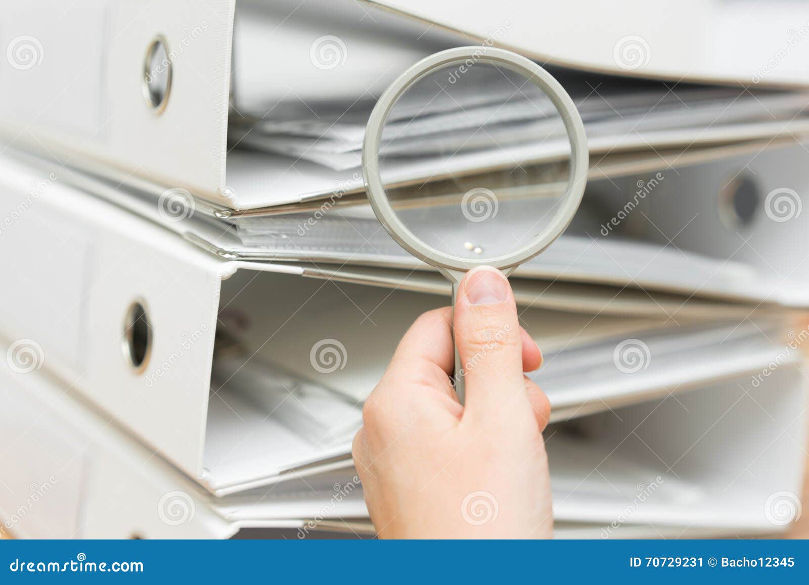 Closeup Of Hand Using Of Magnifying Glass To Inspect Stack Of Do Stock