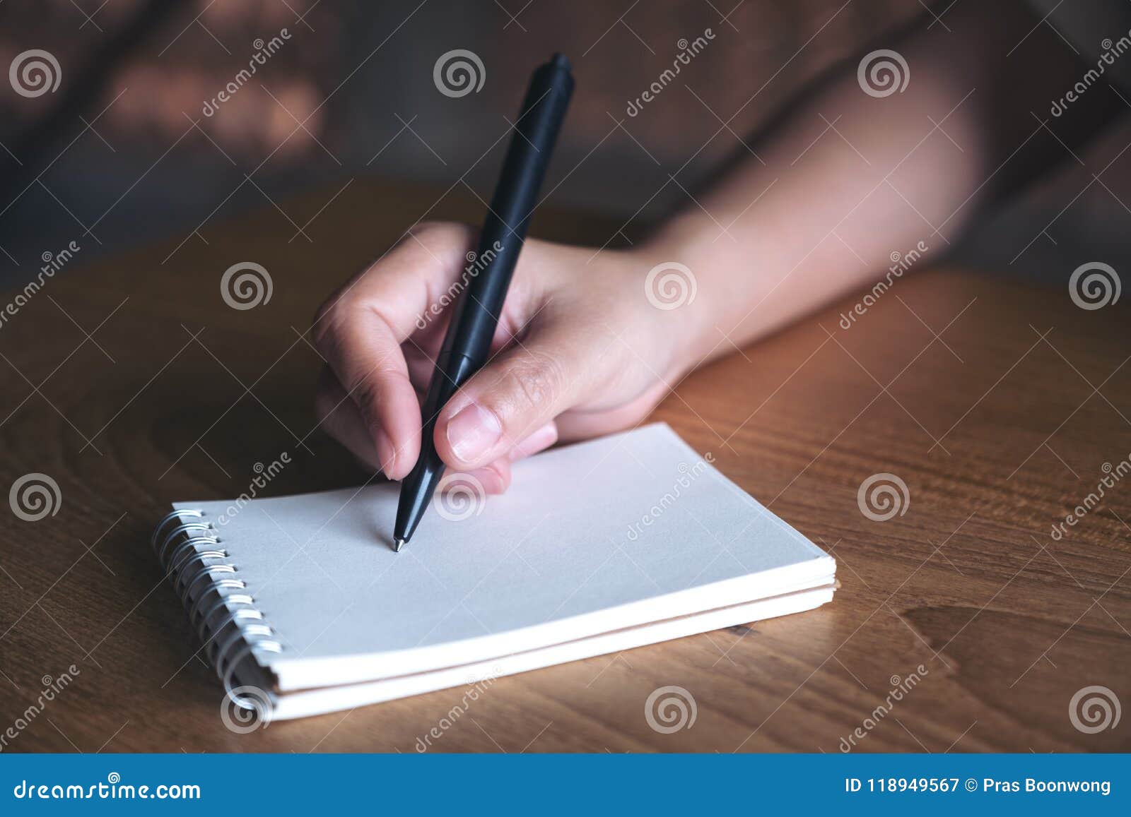 A Hand Writing Down on a White Blank Notebook on Wooden Table Stock ...