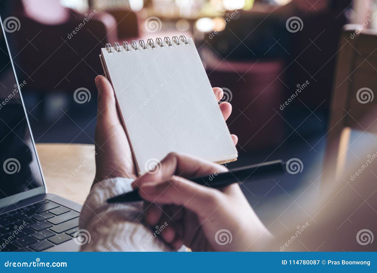 Hands Holding and Writing Down on a Blank Notebook with Computer Laptop ...