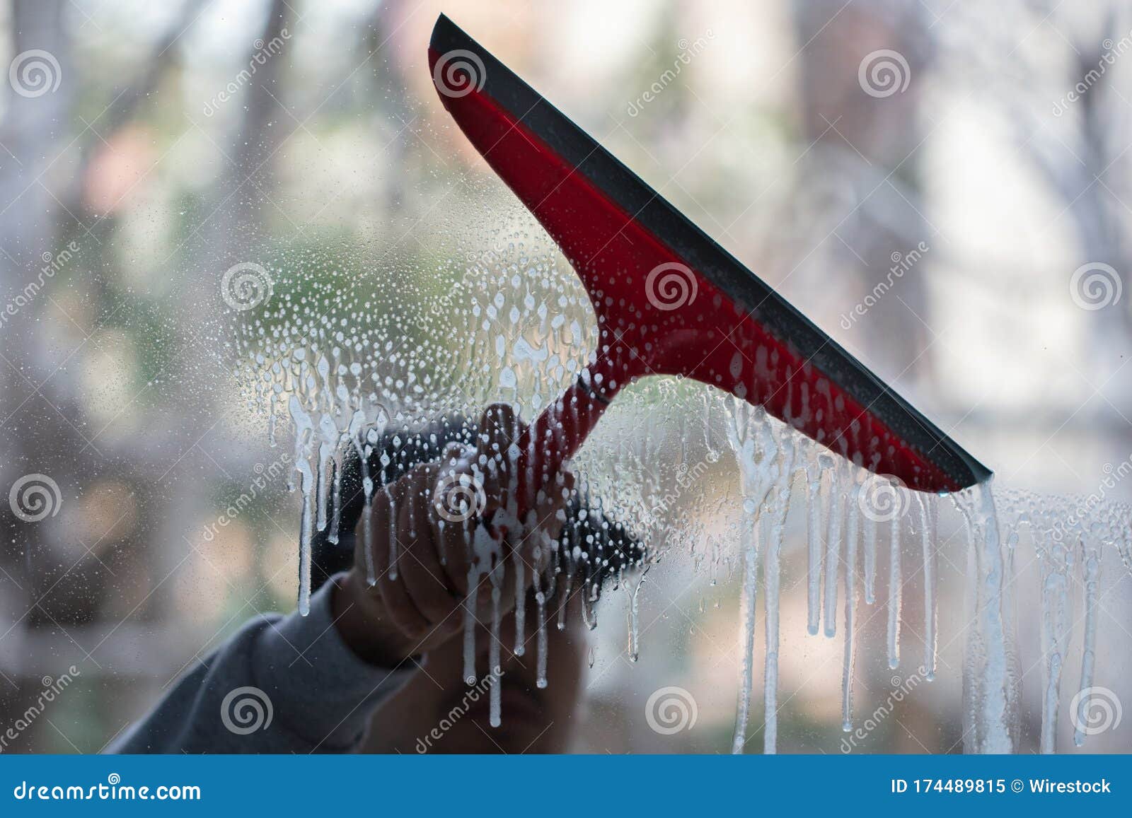 Closeup of a Person Cleaning Windows with a Red Squeegee Under the ...