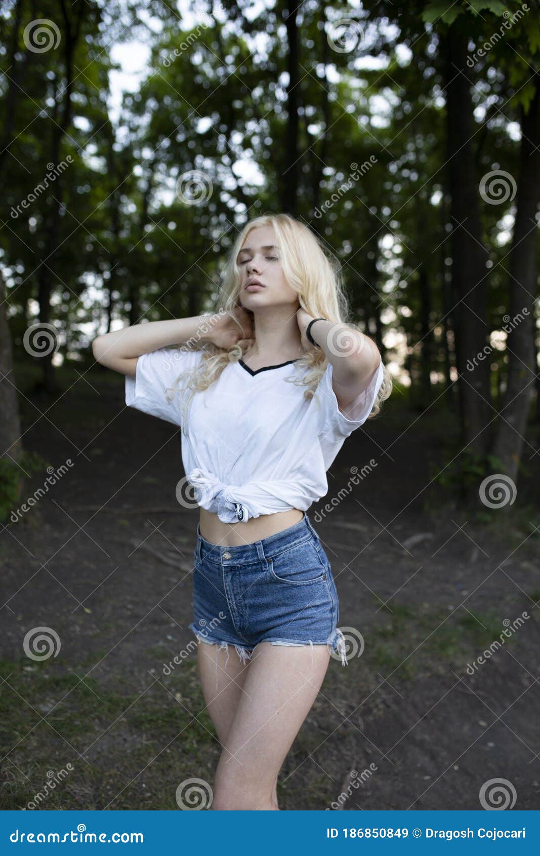 Sensual Blonde Curly Young Woman With Closed Eyes Holding Her Hands Behind Neck Dress Denim