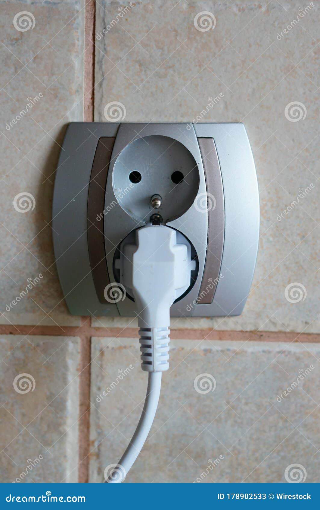 Closeup of Power Outlets on a Tiled Wall with a Plug in One of Them ...