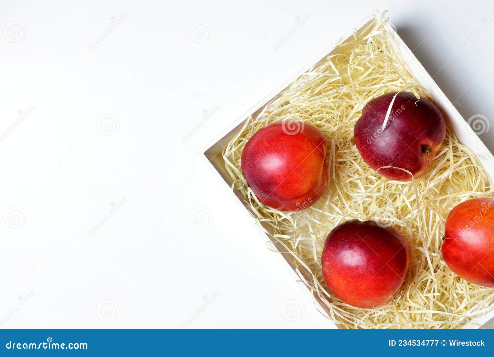 Closeup Shot of Four Nectarines in a Box with Straw on a White ...