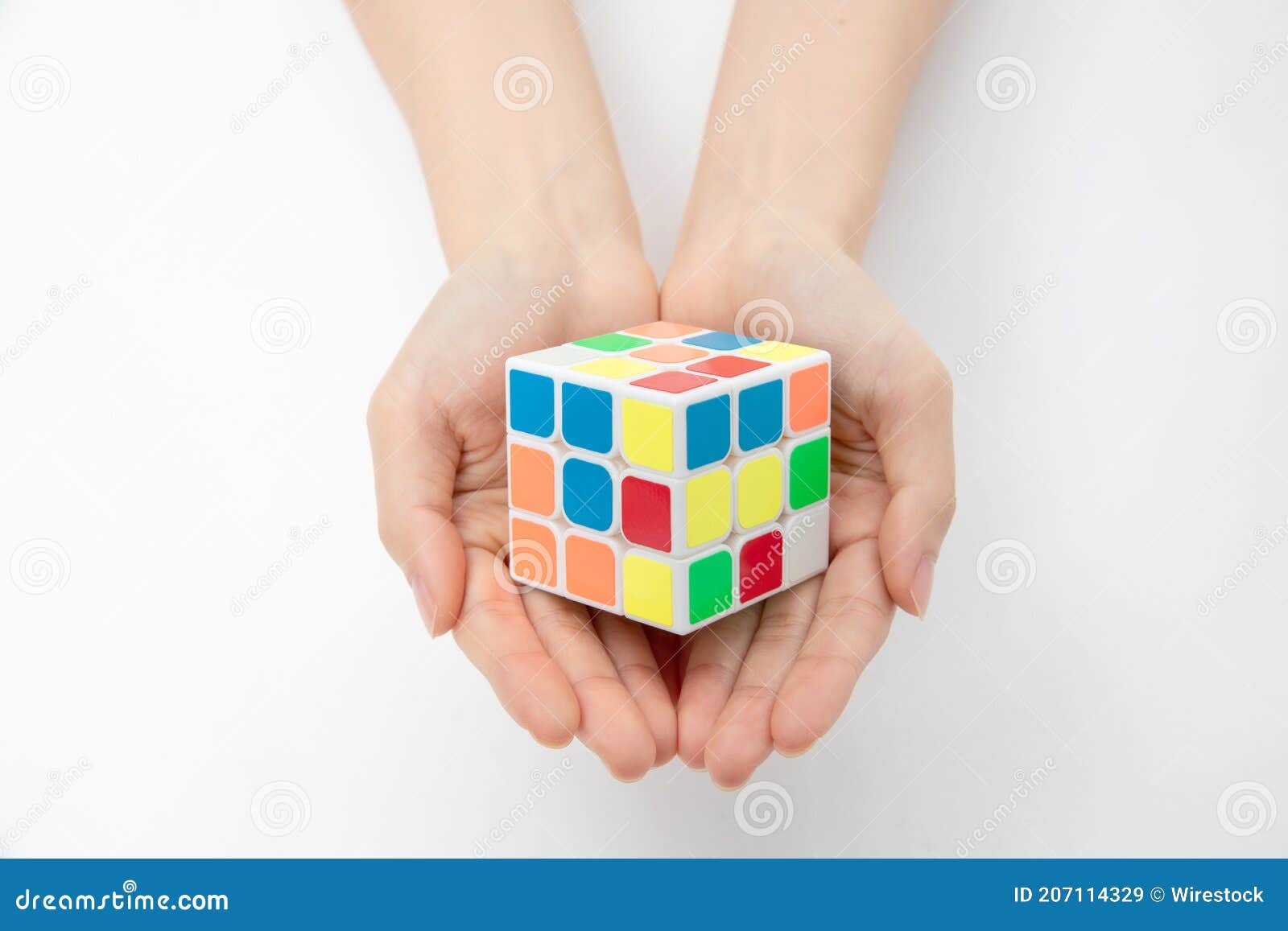 Closeup Shot Of Hands Holding A Colorful Rubiks Cube On A White Surface ...
