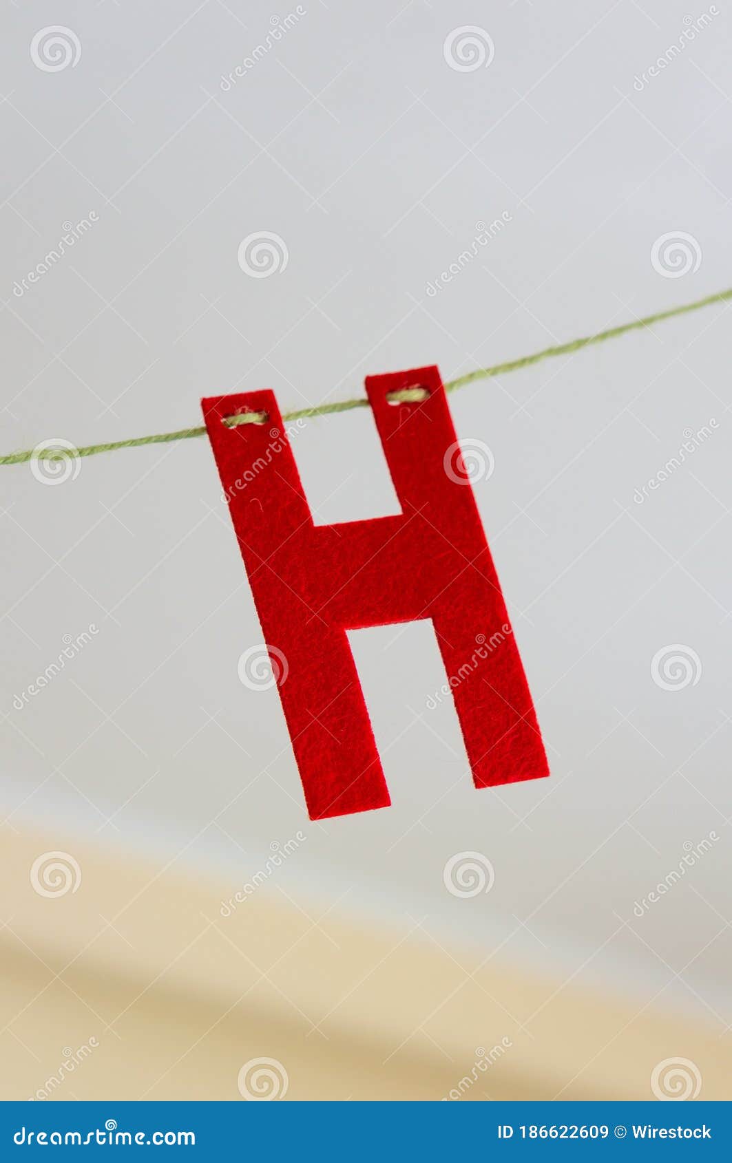 Closeup Shot of a Red H Letter Hanging on a Cable with a Blurred ...