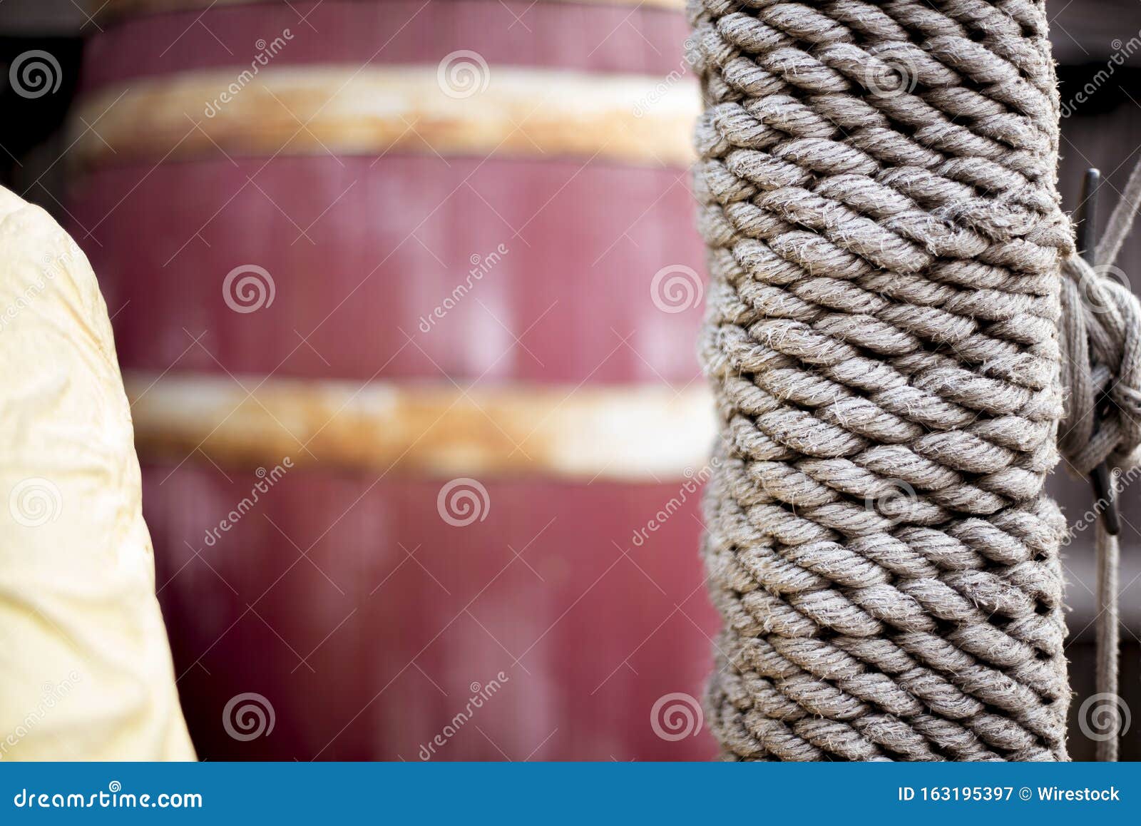 Closeup Shot of a Rope Wrapped Around a Pole with a Blurred Barrel in ...