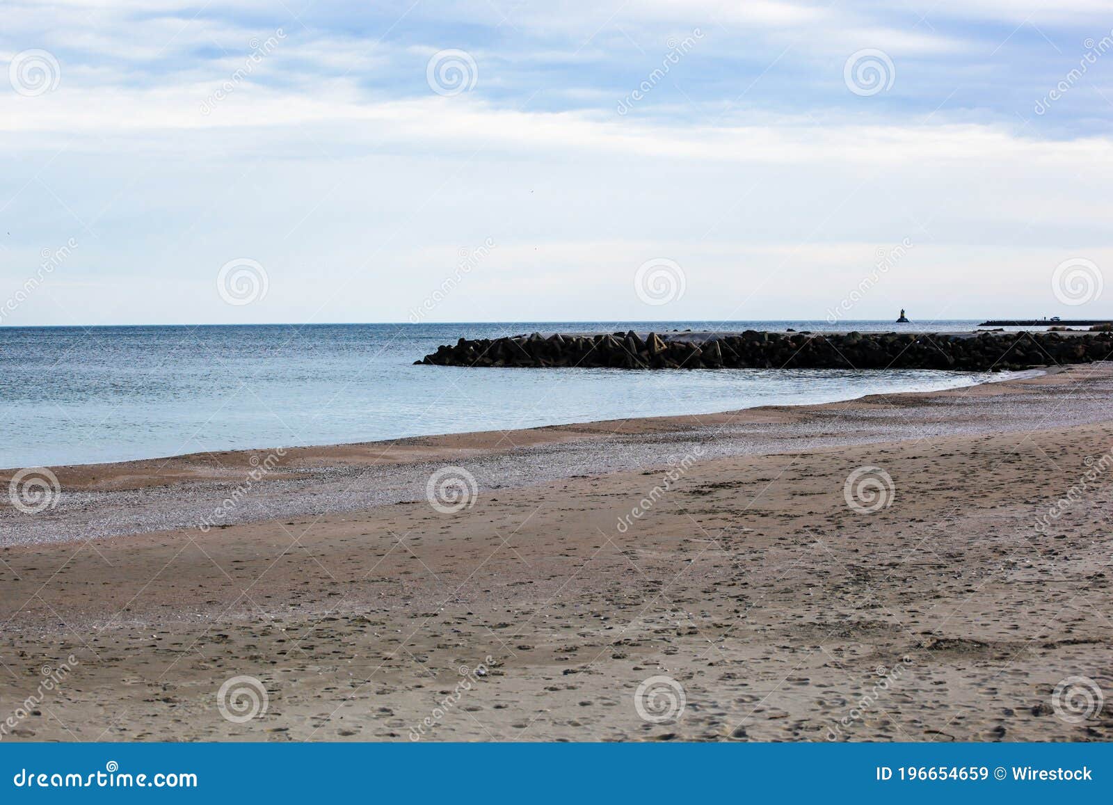 Closeup Shot of a Sandy Beach with the Ocean and a Stone Dock on the ...