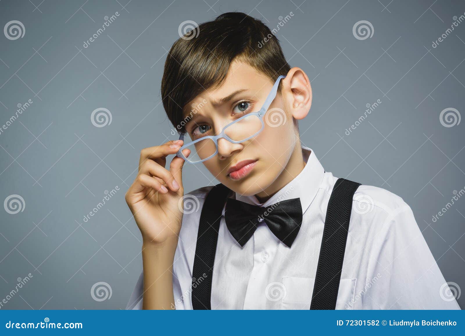 Closeup Thoughtful Young Boy with Hand on Glasses Against Gray ...
