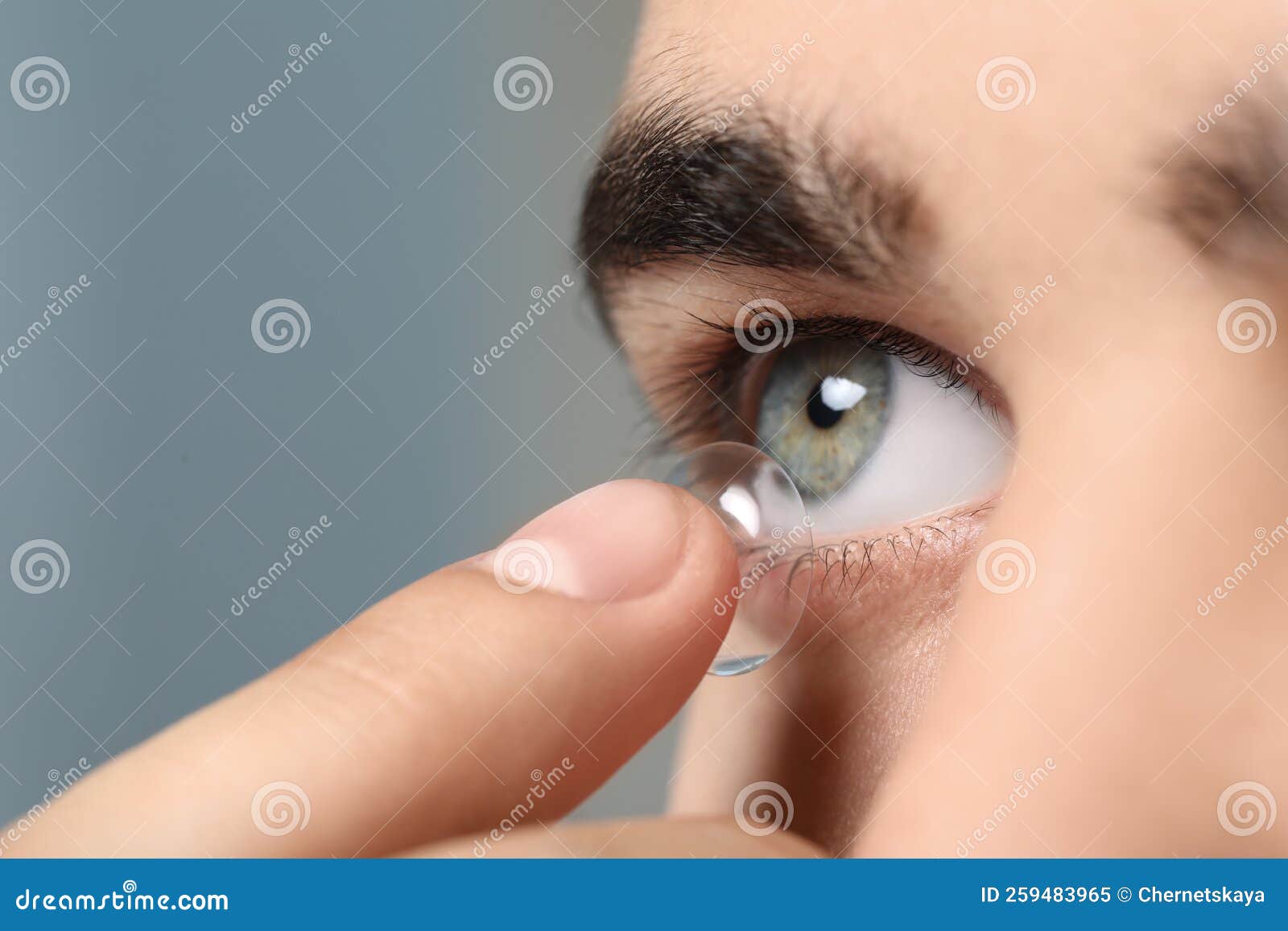 Closeup View of Young Man Putting in Contact Lens on Grey Background ...