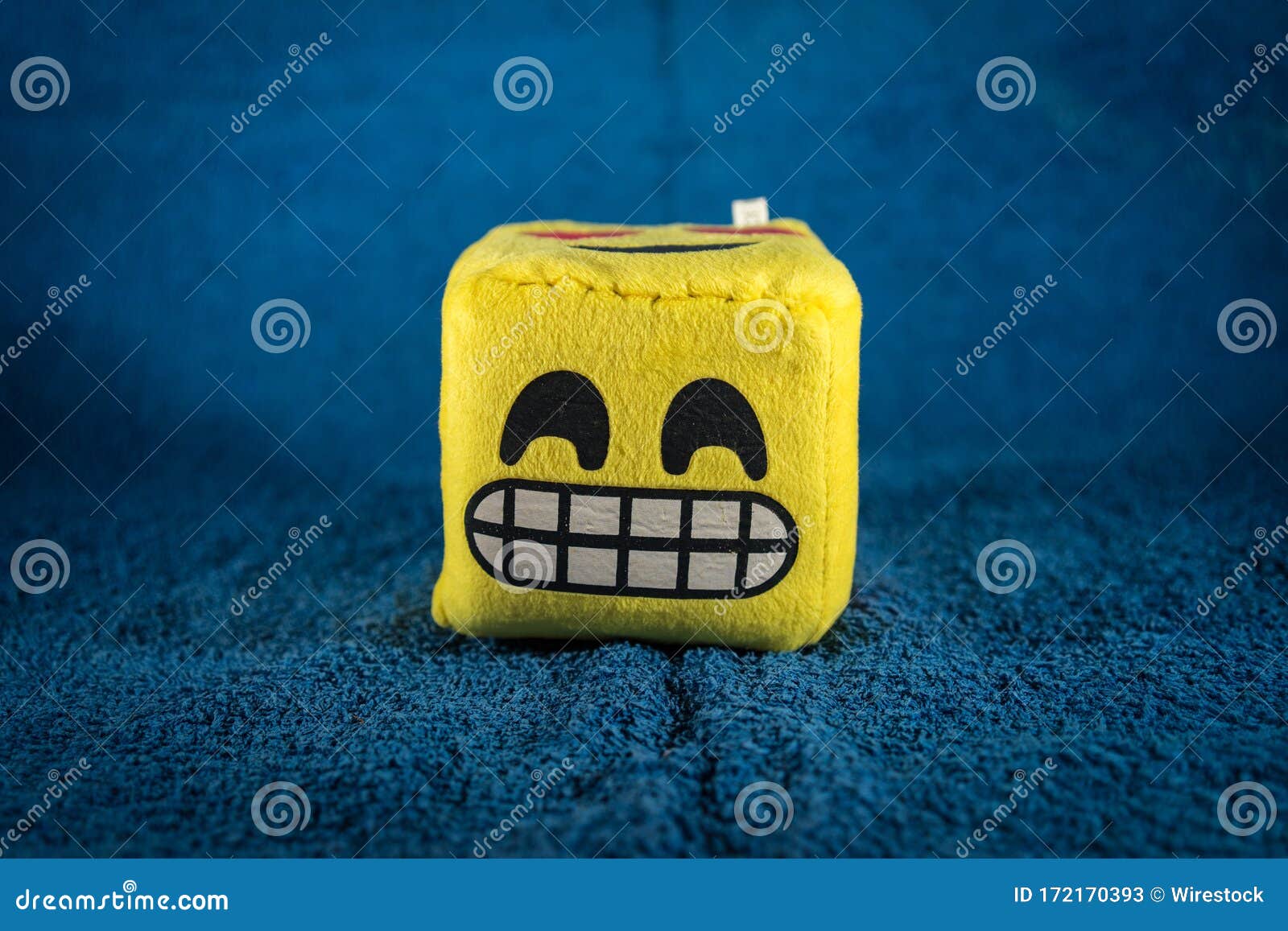 Closeup of a Yellow Toy Cube with a Smiley Face Under the Lights with a ...