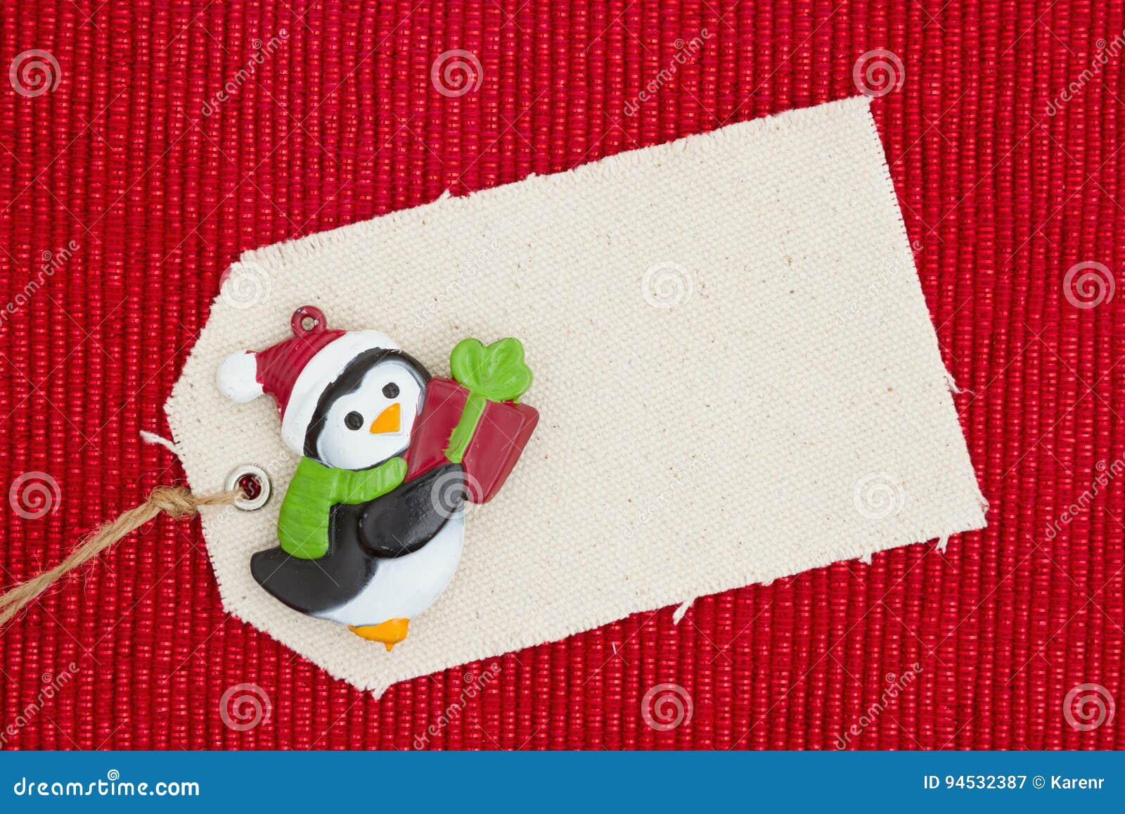 A Cloth Gift Tag with a Christmas Penguin on Shiny Red Material Stock ...