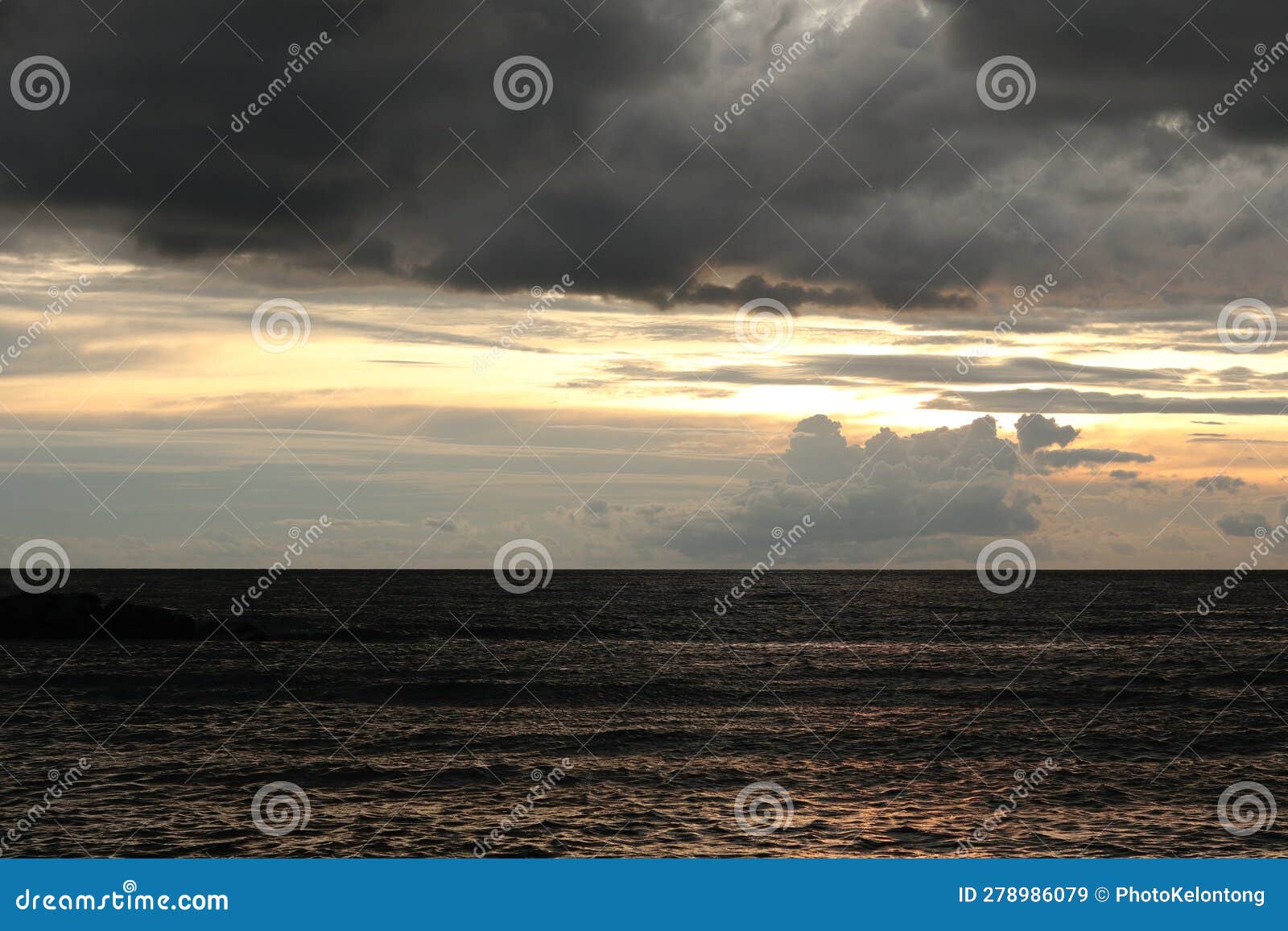 A Cloudy Sky Over the Ocean with a Dark Sky and the Sun Setting Behind ...