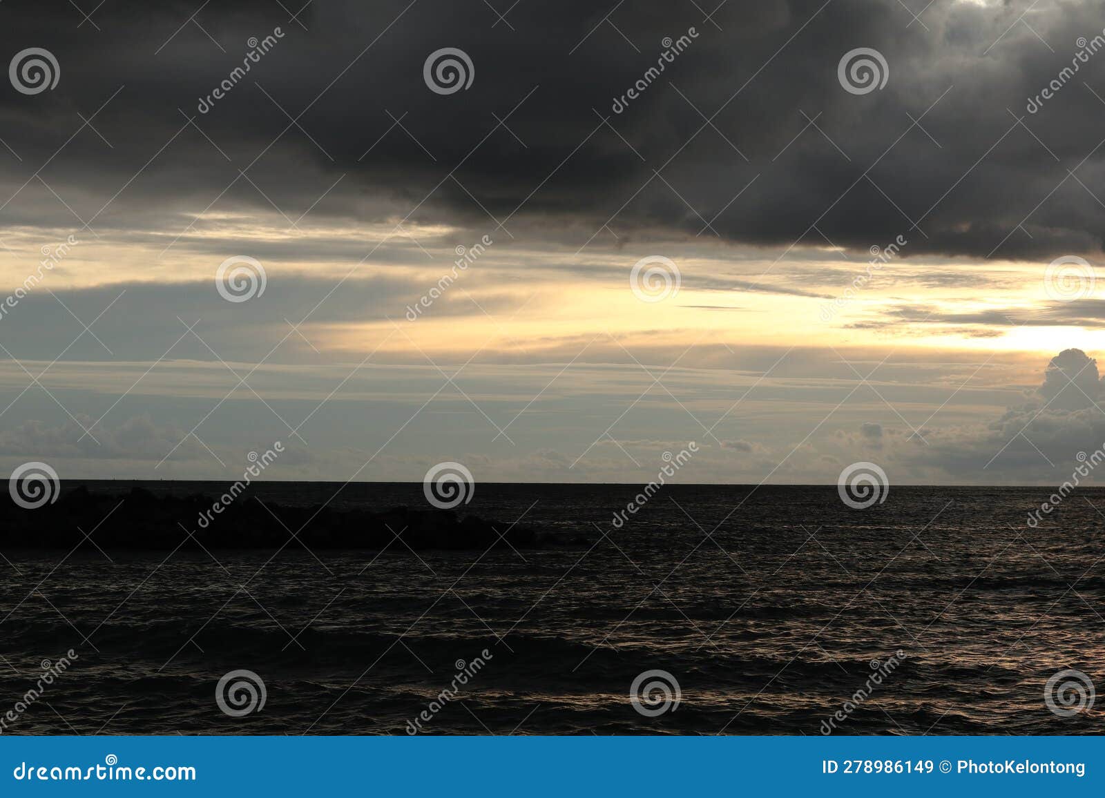 A Cloudy Sky Over the Ocean with a Dark Sky and the Sun Setting Behind ...