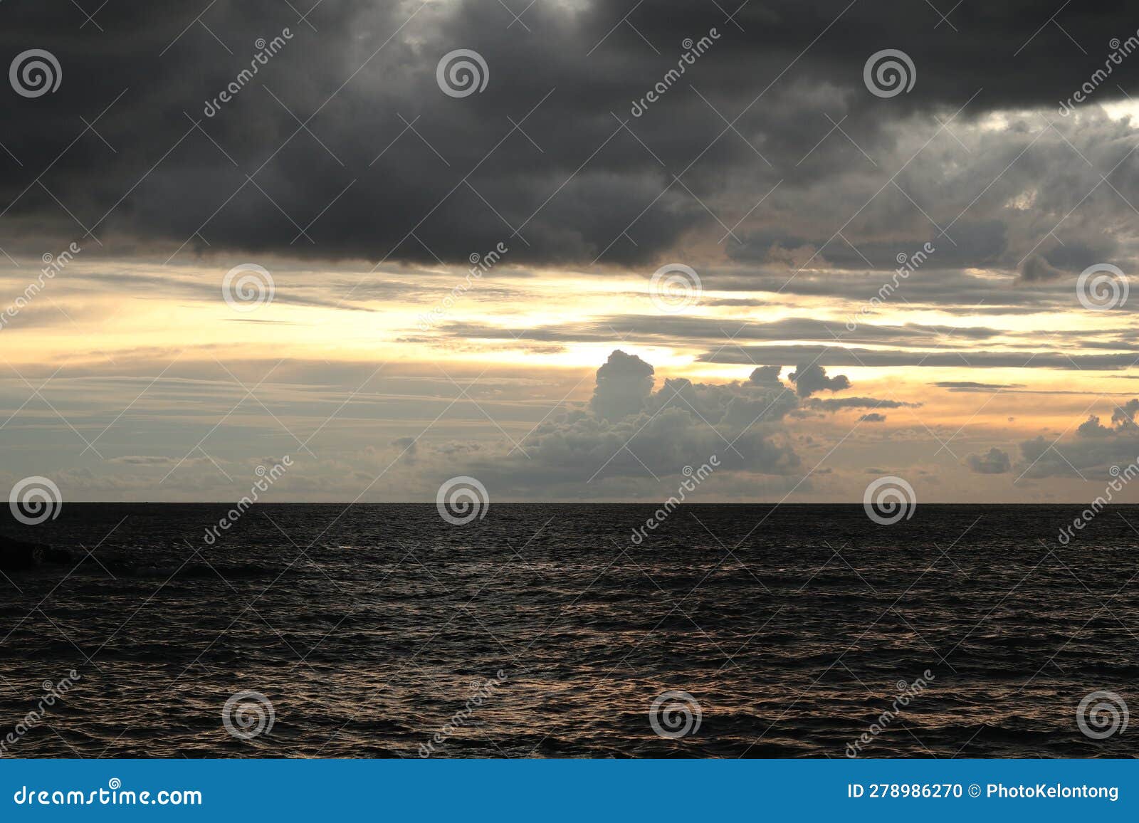 A Cloudy Sky Over the Ocean with a Dark Sky and the Sun Setting Behind ...