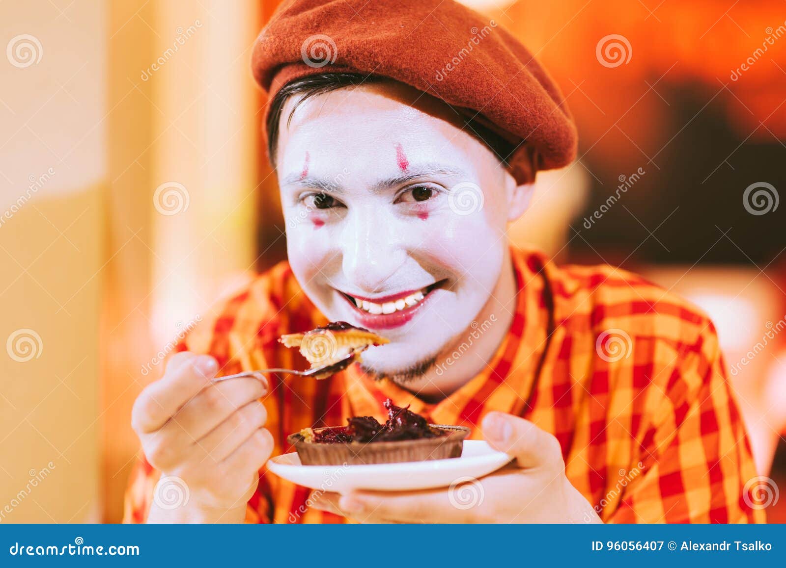 The Clown is Eating a Cake in a Cafe and His Face is Croaking. Stock ...