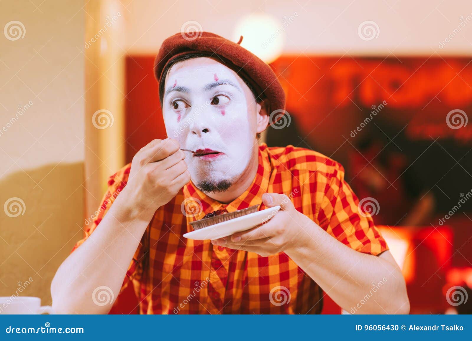 The Clown is Eating a Cake in a Cafe and His Face is Croaking. Stock ...