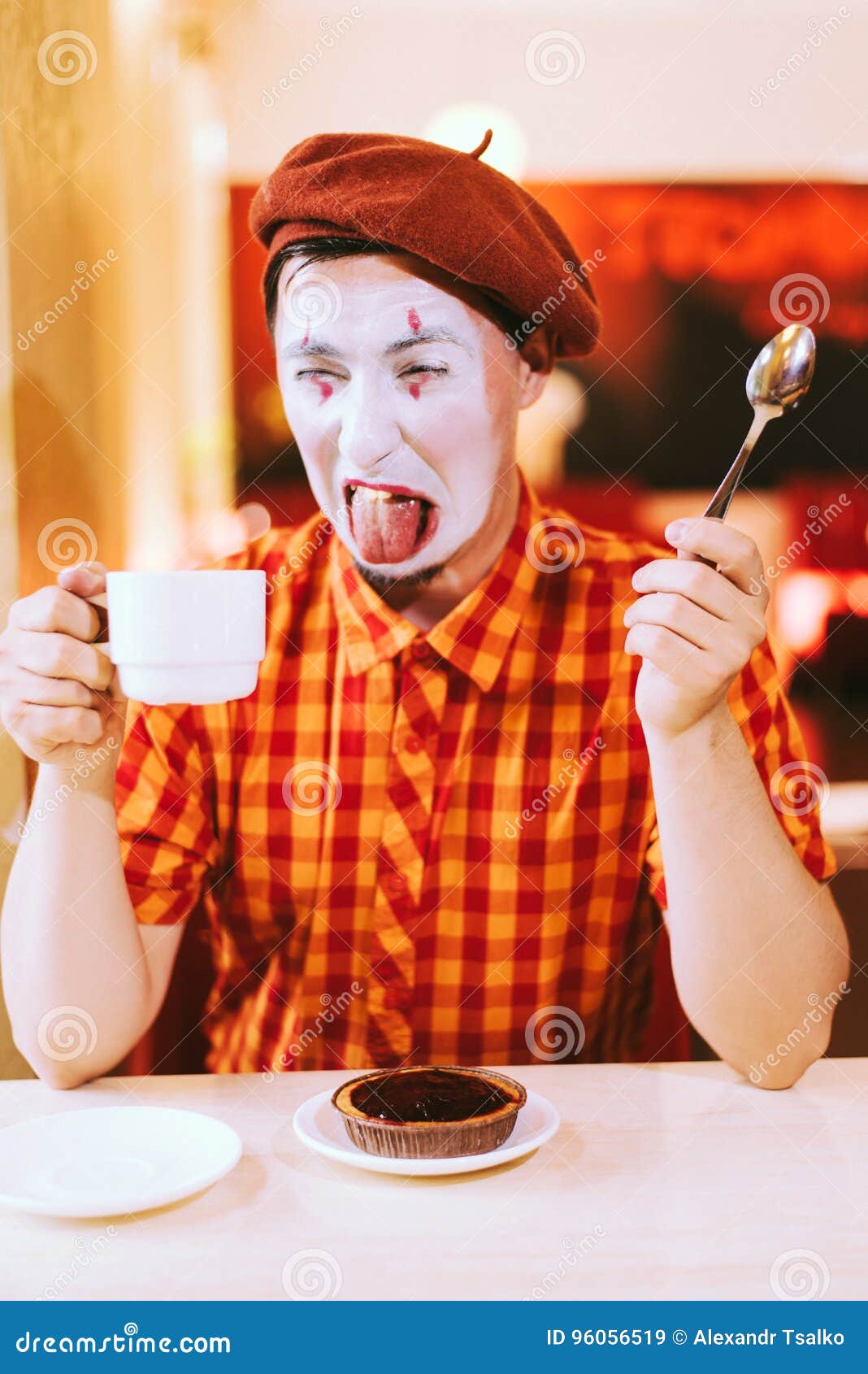 The Clown is Eating a Cake in a Cafe and His Face is Croaking. Stock ...