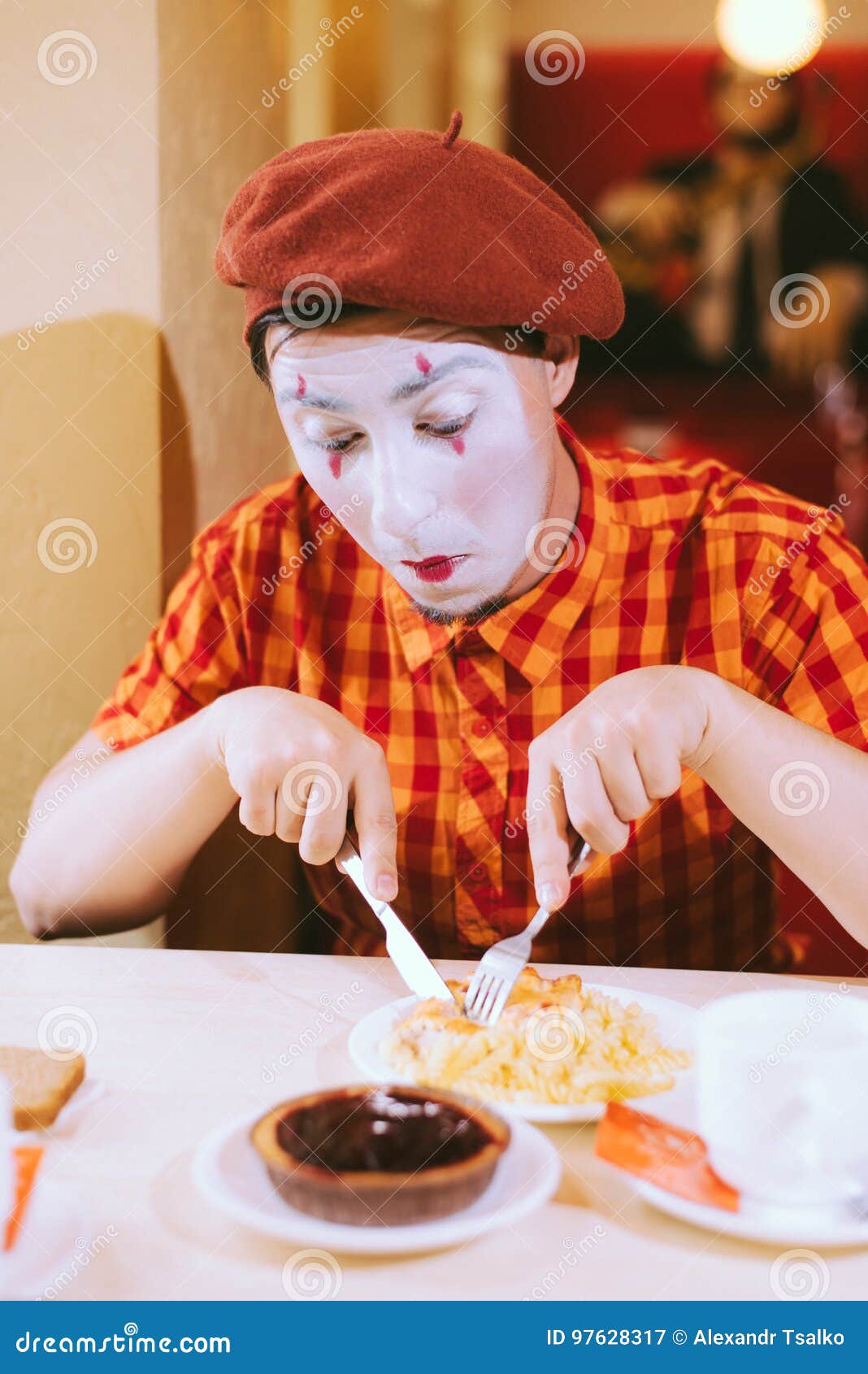 The Clown is Eating a Cake in a Cafe and His Face is Croaking. Stock ...