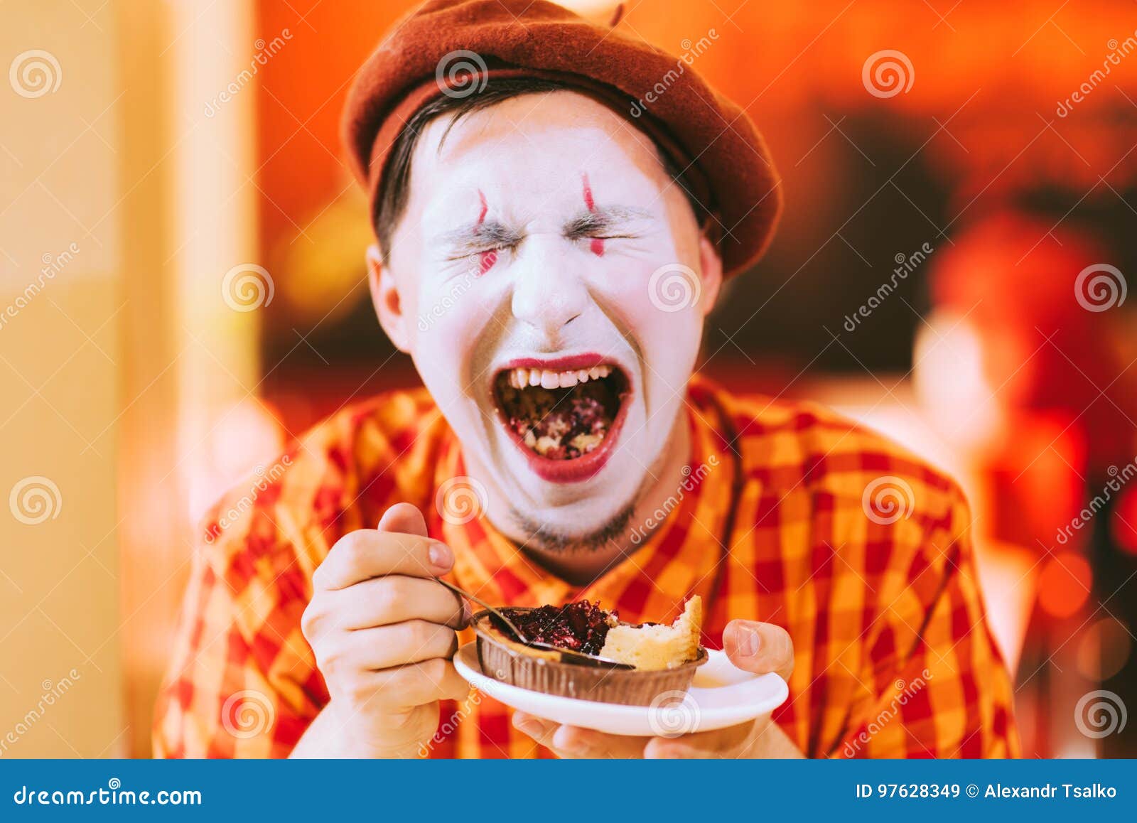 The Clown is Eating a Cake in a Cafe and His Face is Croaking. Stock ...