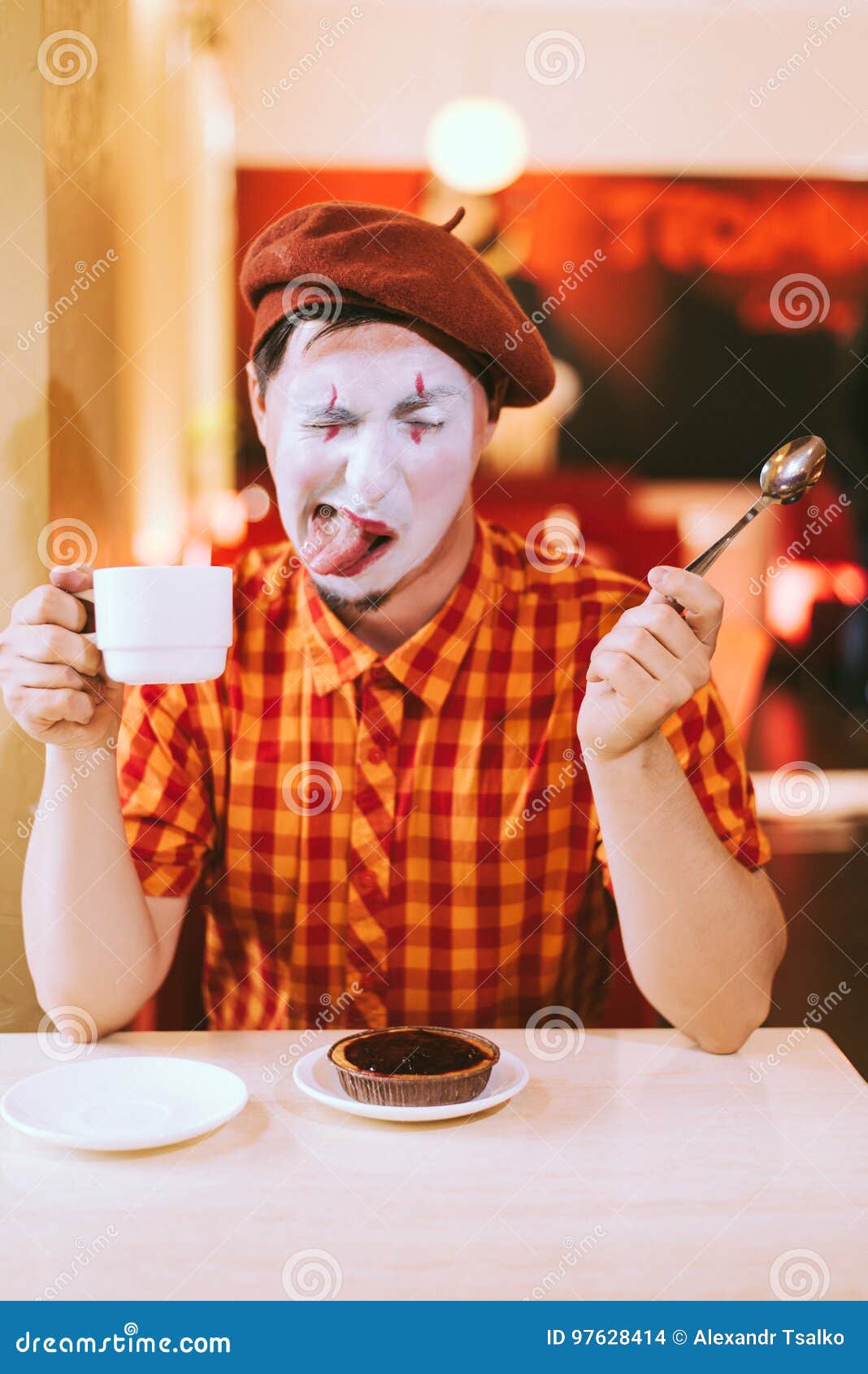 The Clown is Eating a Cake in a Cafe and His Face is Croaking. Stock ...