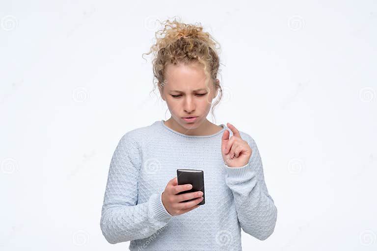 Clueless Young Curly Girl Having Troubles With Her Smartphone Stock