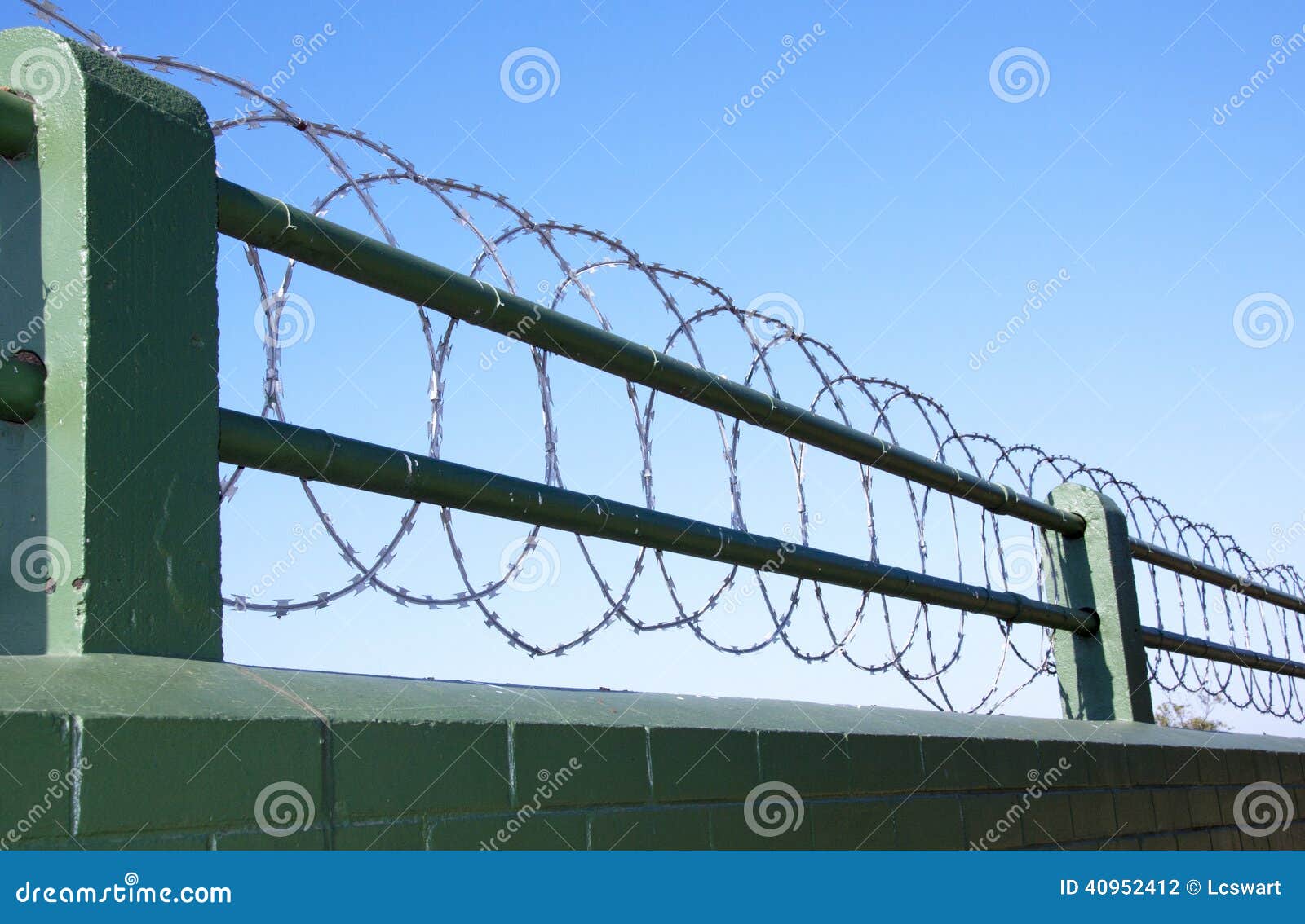 Coiled Razor Wire Barrier Atop Green Painted Brick Wall Stock Photo ...