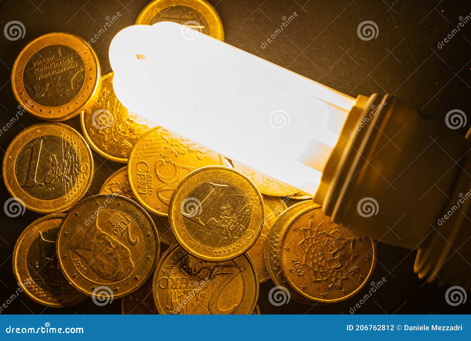 Coins and Light Bulb on a Dark Surface Stock Photo - Image of ...