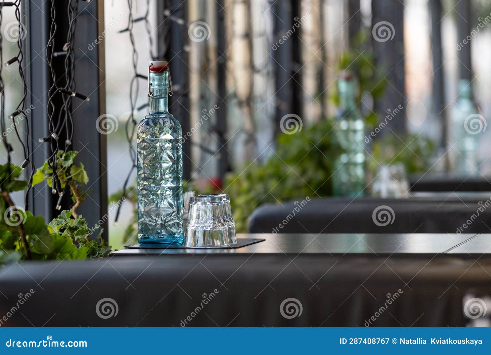 Cold Fresh Water in Old-fashioned Bottle with Glasses on a Cafe Table ...