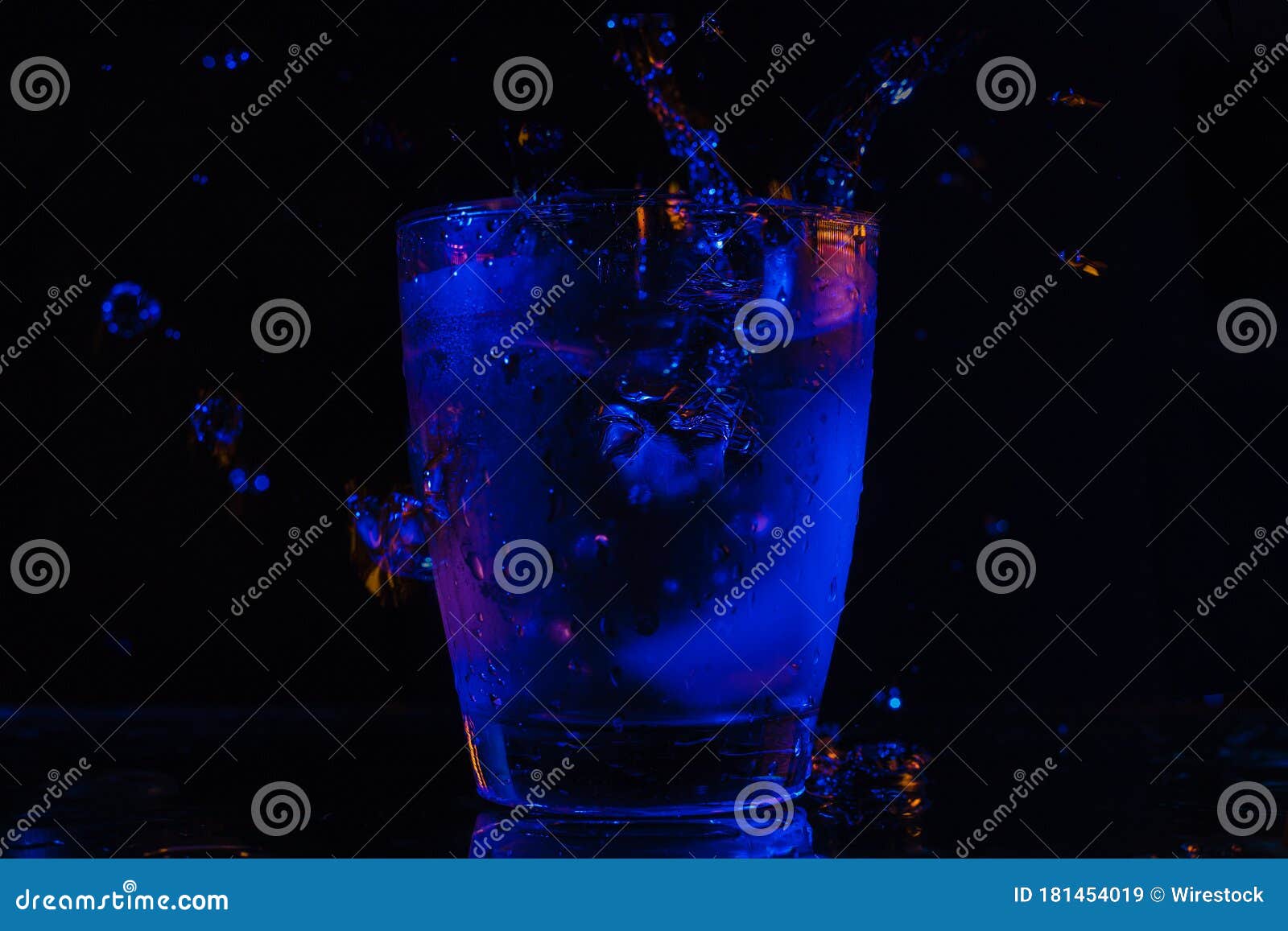 Cold Liquid Splash in a Glass on the Table Under the Colourful Lights ...