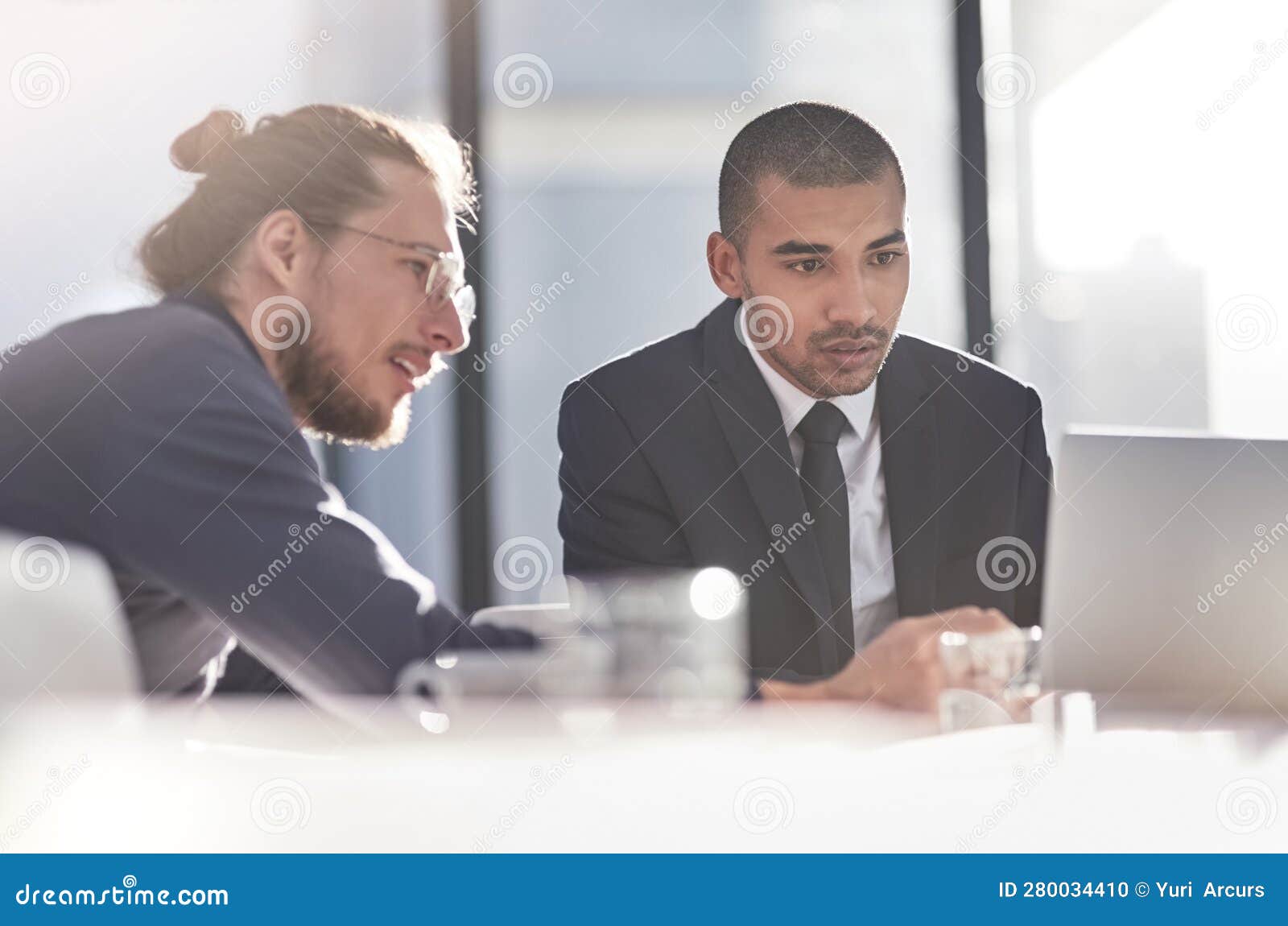Collaborating in Real Time Online. Two Young Businessmen Using a Laptop ...