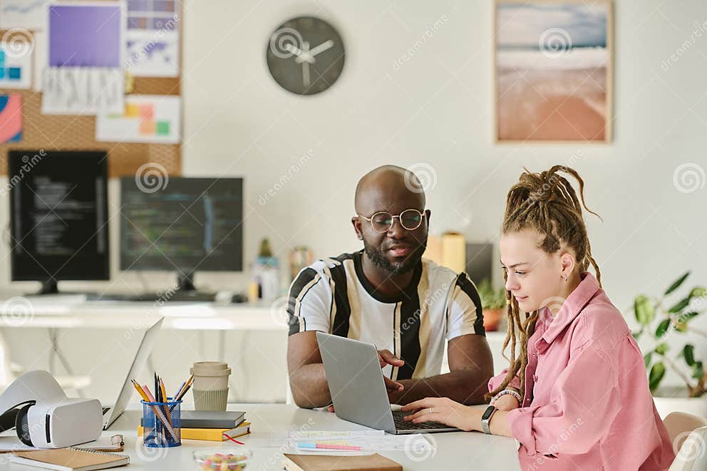 Colleagues Discussing Program on Laptop Stock Photo - Image of office ...