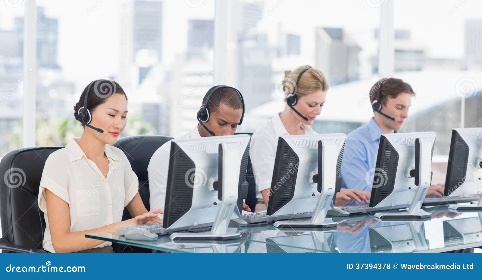 Colleagues with Headsets Using Computers at Desk Stock Photo - Image of ...
