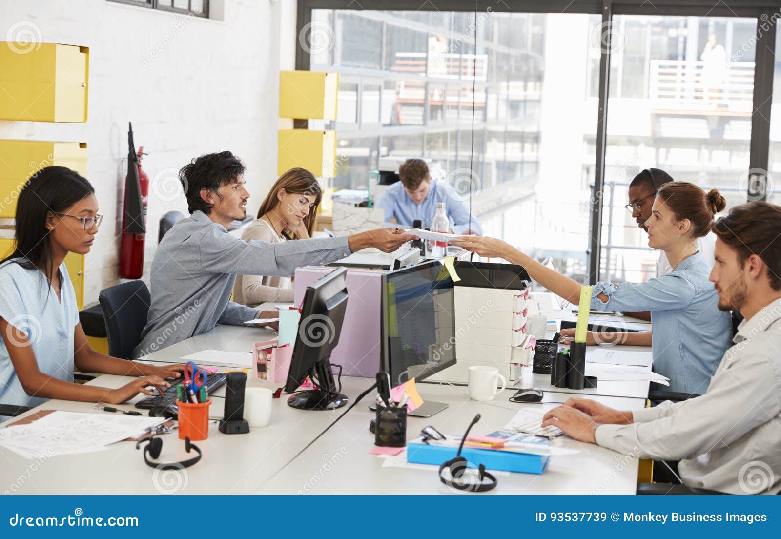 Colleagues Passing Paperwork Across Desk in a Busy Office Stock Image ...