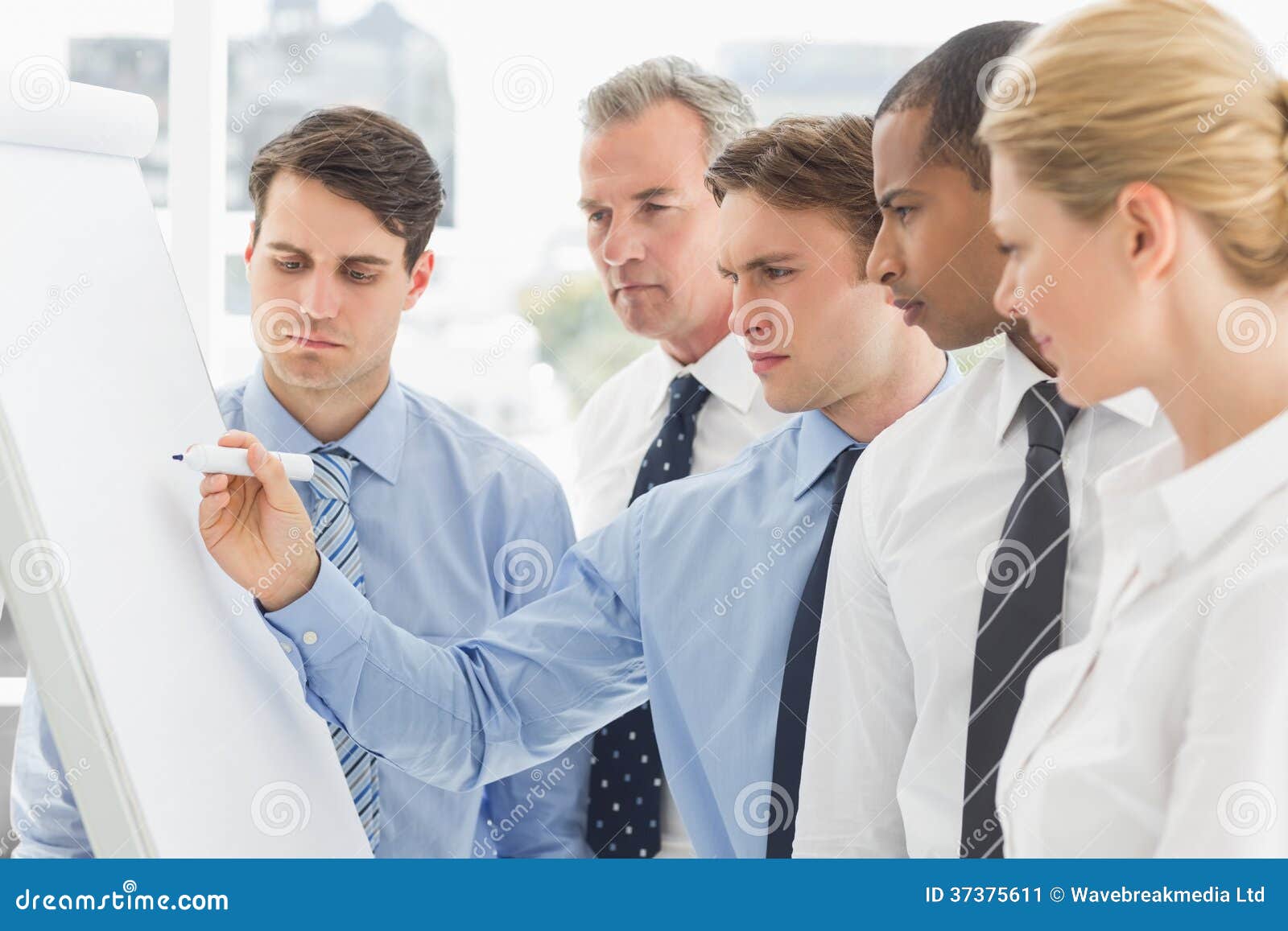 Colleagues Watching Young Businessman Write on Whiteboard Stock Image ...