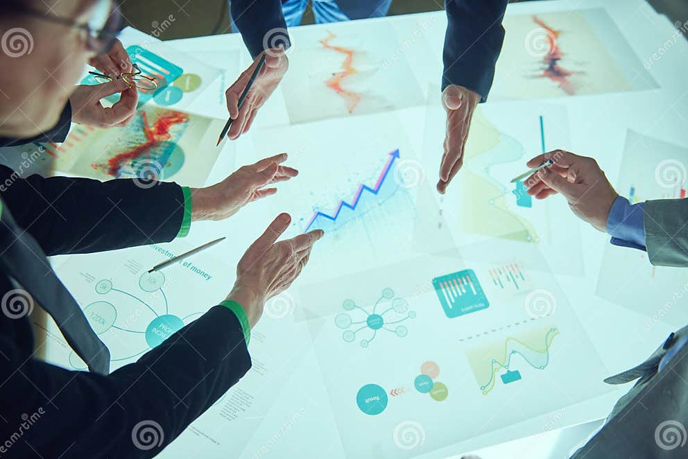 Colleagues Working with Analytical Papers, Checking Graphs and ...