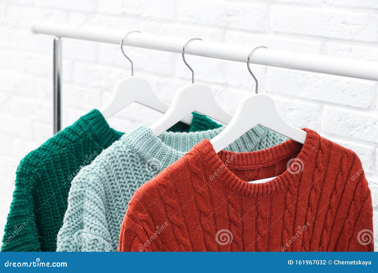 Collection of Warm Sweaters Hanging on Rack Near Wall Stock Photo ...