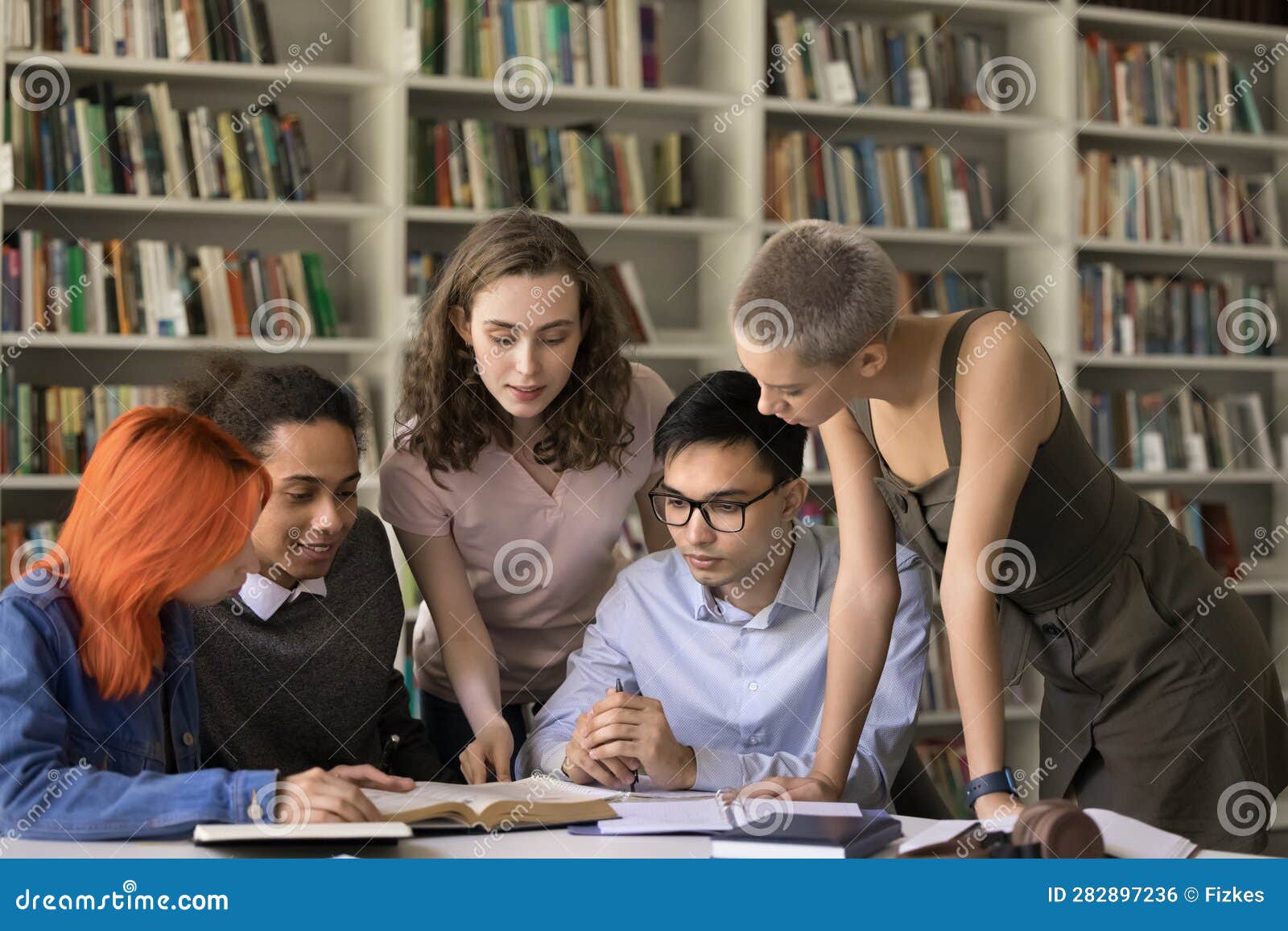 College Classmates Reading Textbook in Campus Library Together Stock ...