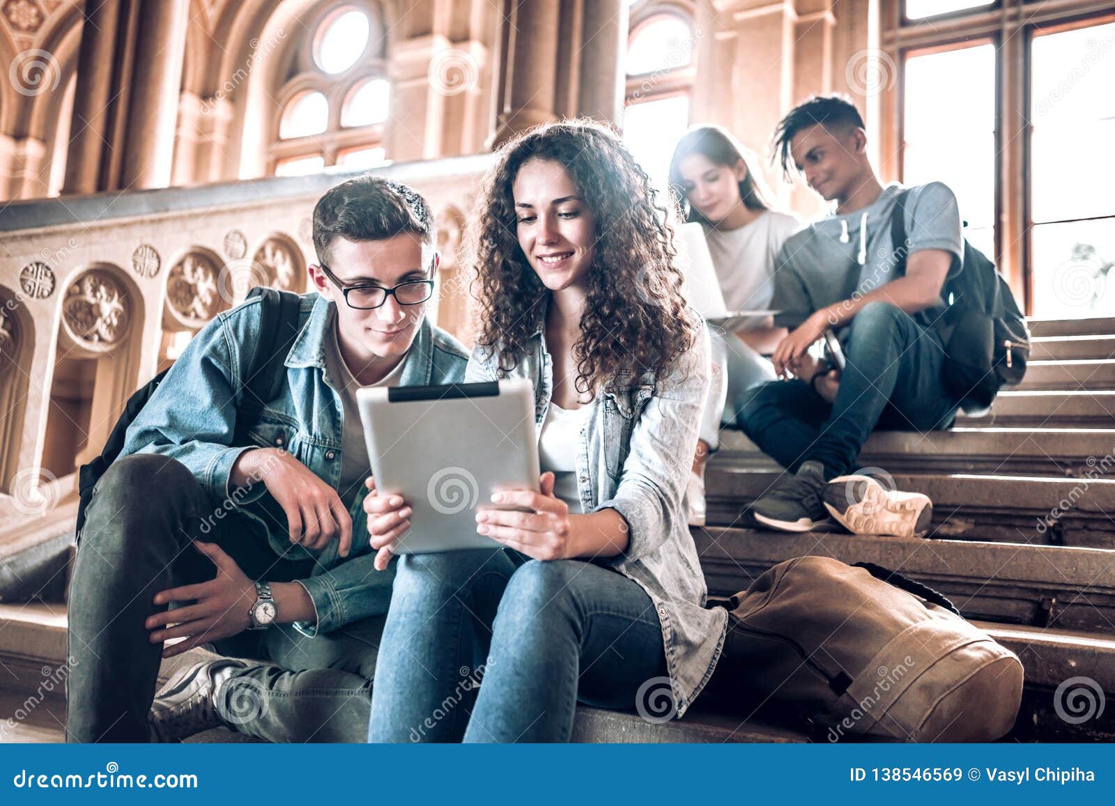 College Life.Group of Students Using a Tablet while Sitting on Stairs ...