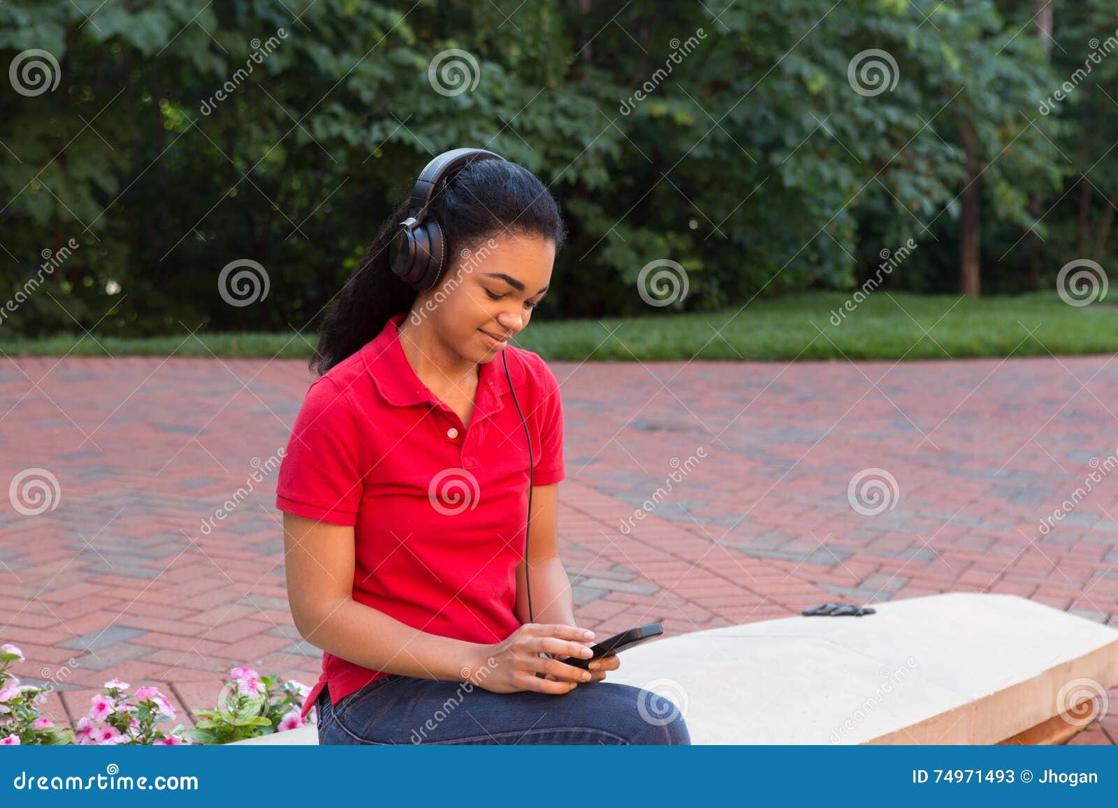 College Student with Headphones and Looking at a Cell Phone Stock Image ...