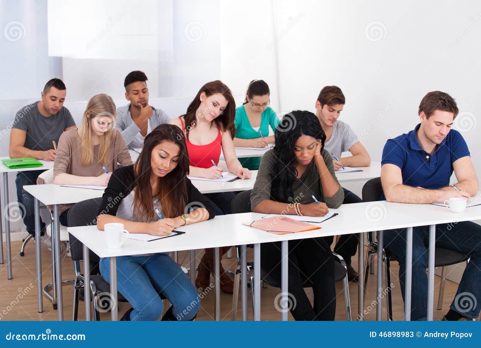 College Students Writing at Desk Stock Image - Image of classmates ...