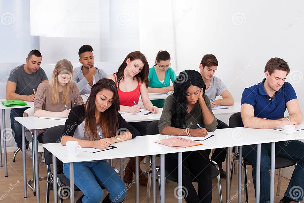 College Students Writing at Desk Stock Image - Image of classmates ...