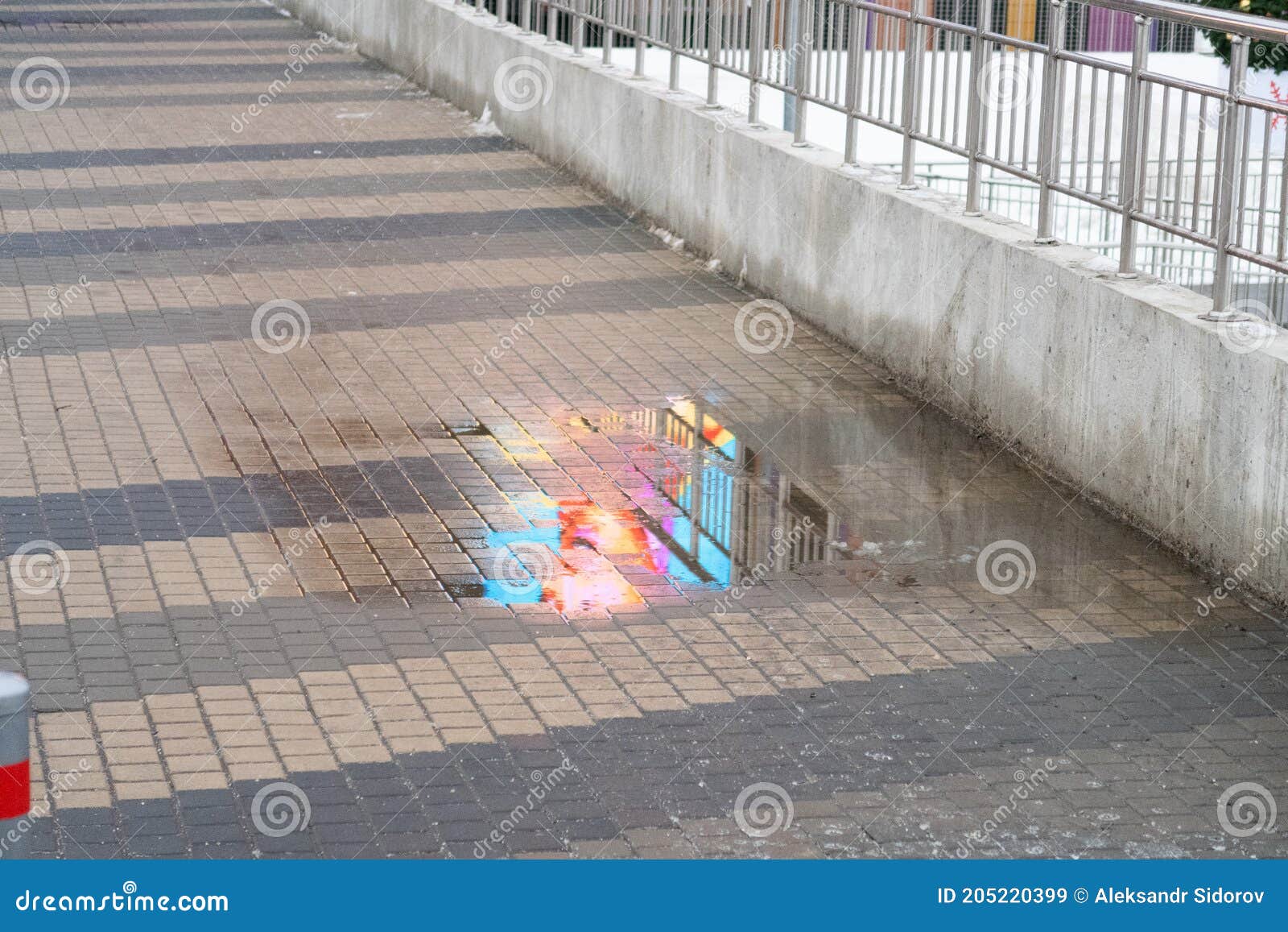 Color Advertising is Reflected in a Puddle on the Pedestrian Sidewalk ...