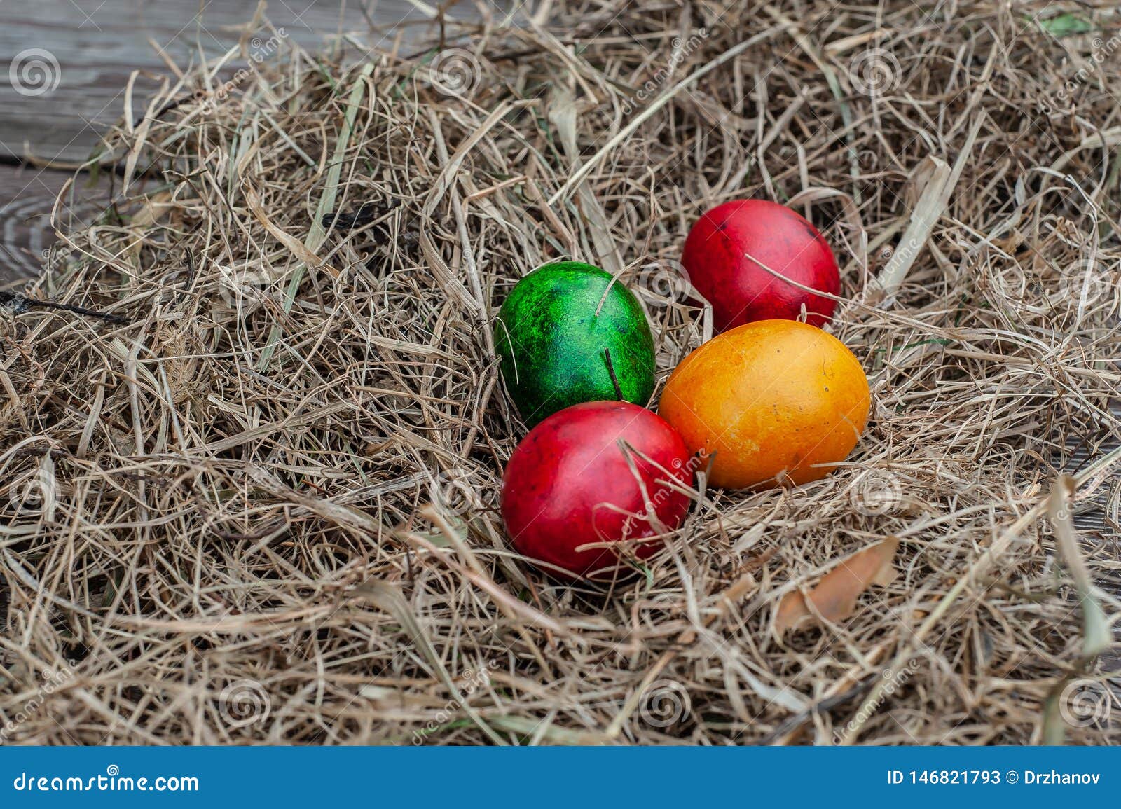 4 Colored Easter Eggs Lays in the Dry Hay on the Wooden Aged Board ...