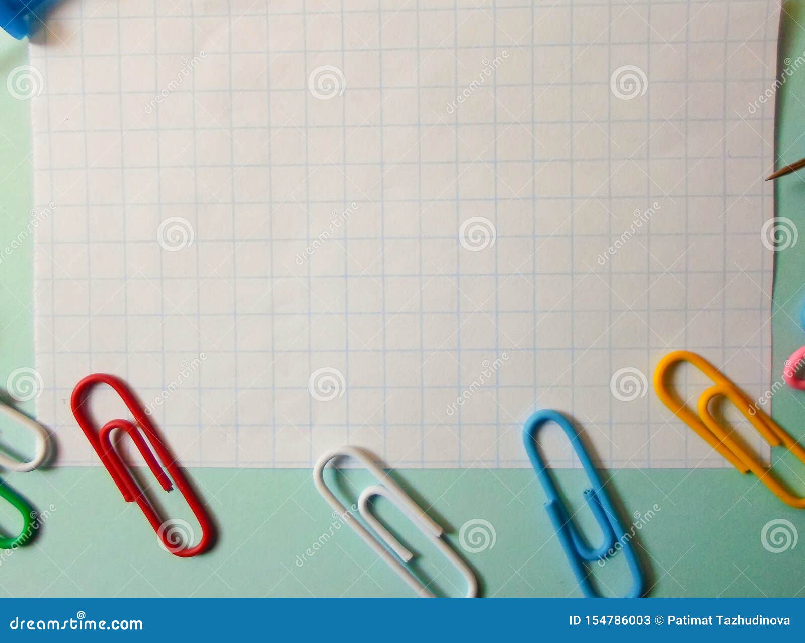 Colored Paper Clips and Pins on a White Sheet of Paper are Scattered ...