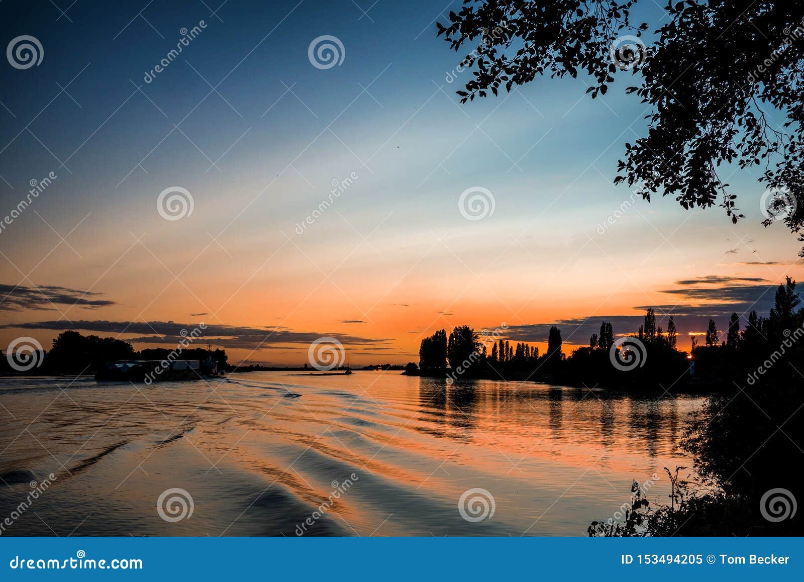 Colorful and Dusky Skies Greet a Barge Floating Down River Stock Image ...