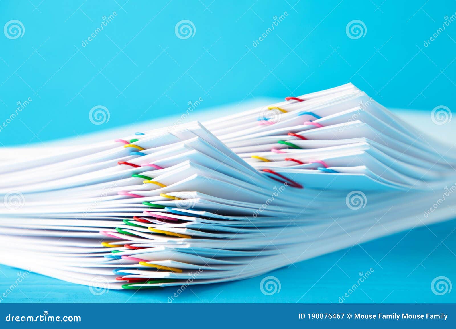 Colorful Paper Clip with Pile of Overload White Paperwork on Blue Stock ...