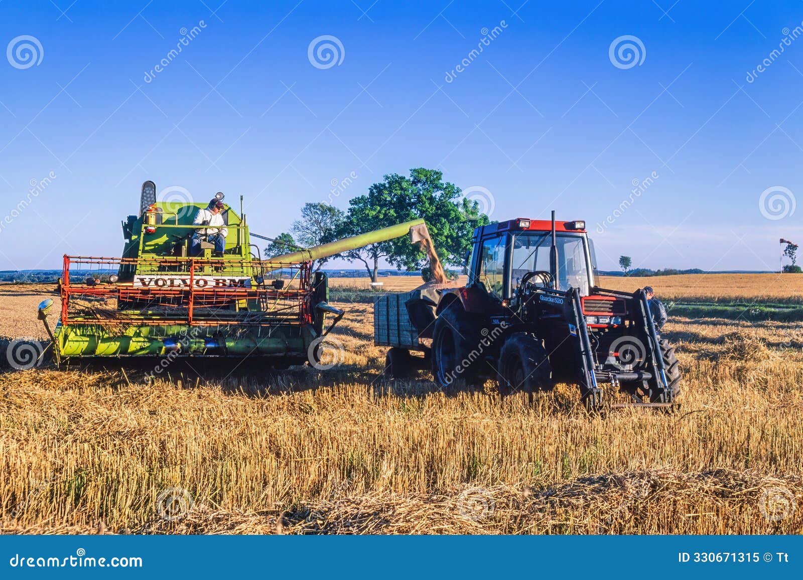 Combine Harvester Unloading Corn on a Cart by a Tractor Editorial Image ...