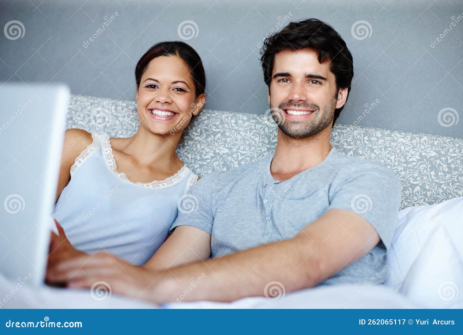 Comfy in Bed with Technology. Attractive Couple in Bed Looking at a ...