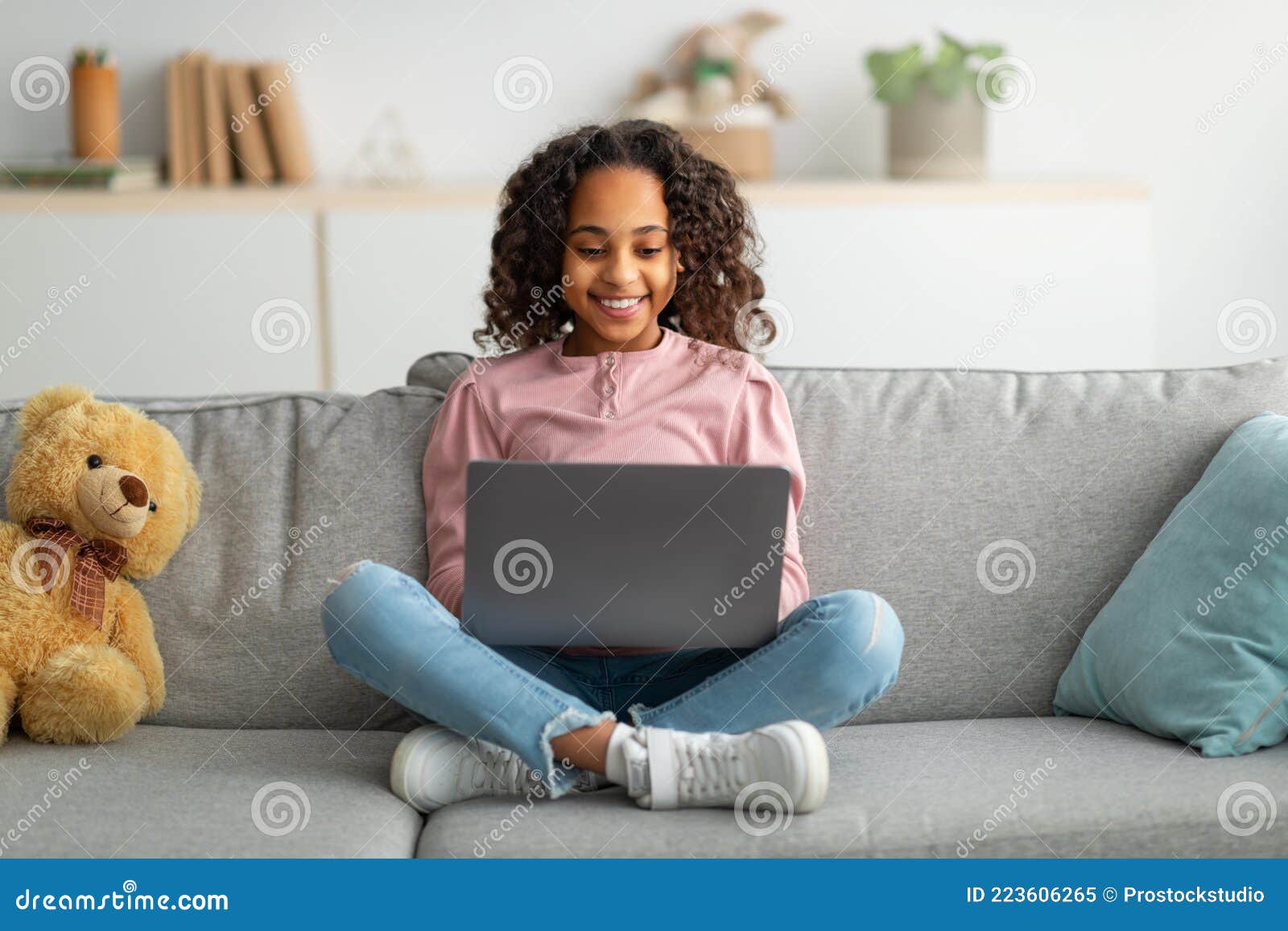 Communication and Technology. Smiling Black Teen Girl Sitting on Sofa ...